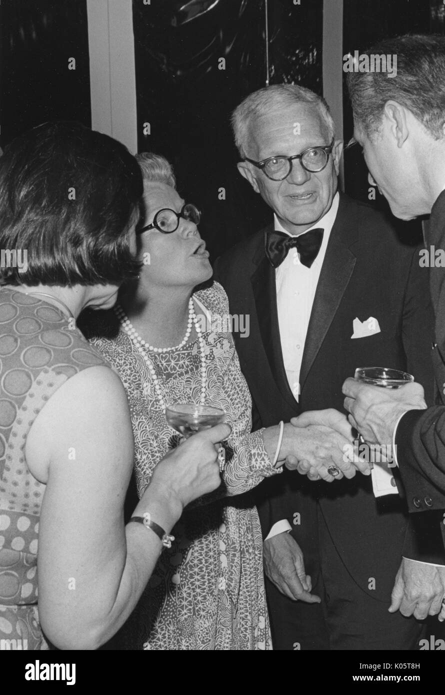 Two men and two women attending the Centennial Ball, two are shaking ...