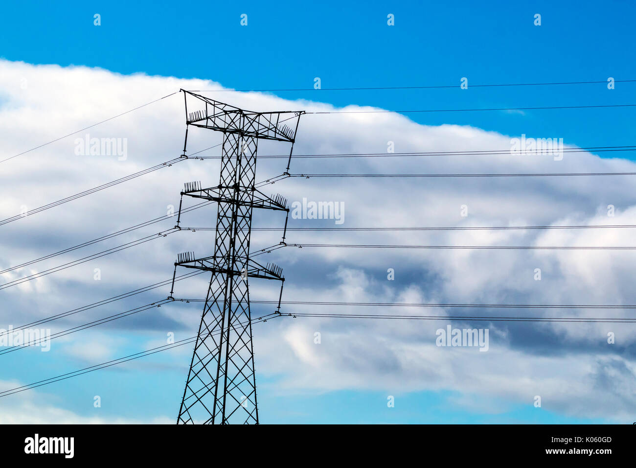 Power grid overhead electricity pylon and cables against blue cloudy ...