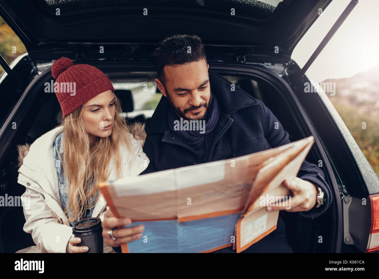 Young couple using a map on a road trip for directions. Young man and ...