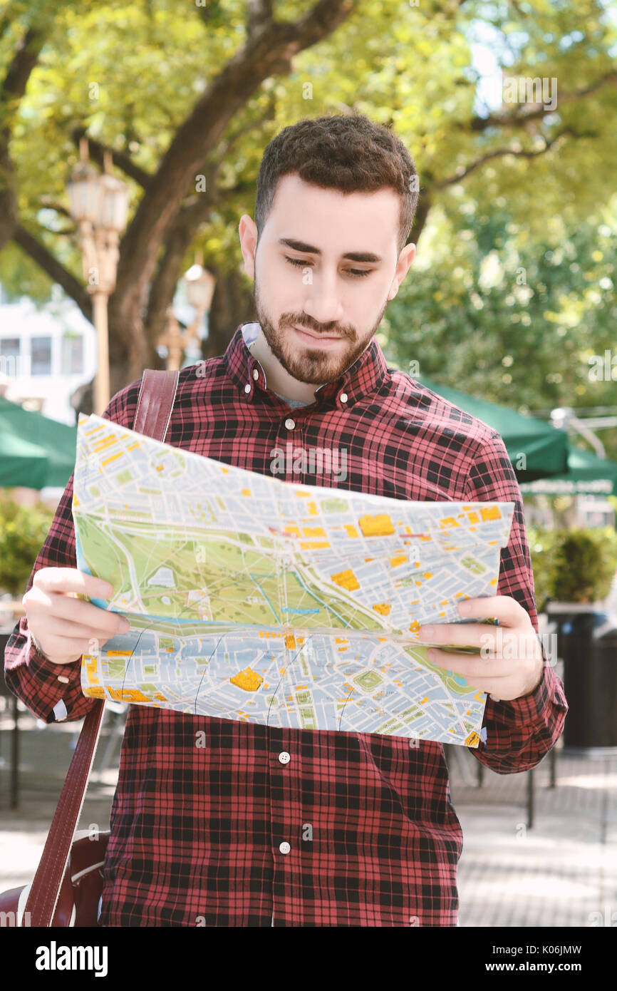 Portrait of a young handsome tourist man looking at a map. Tourism ...