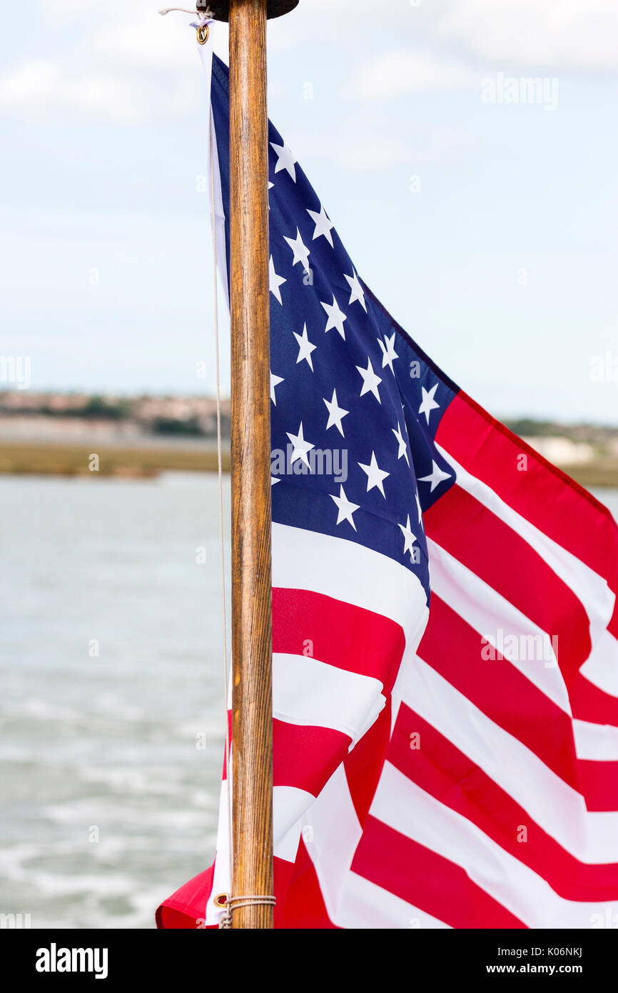 American flag fluttering from stern of boat. Close up, river behind ...