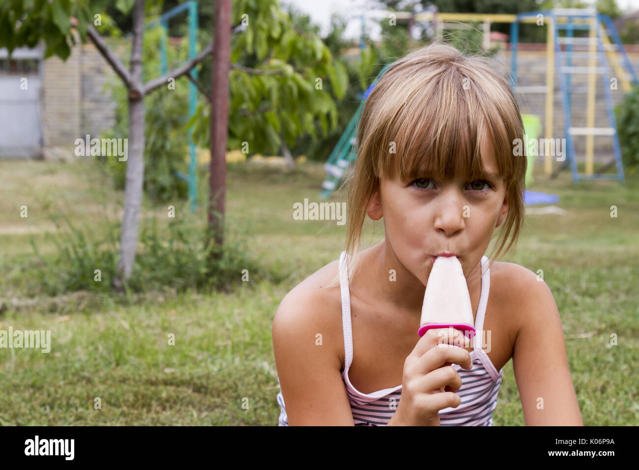 Beautiful Child Eating Ice Cream Outdoors In Spring Park Against