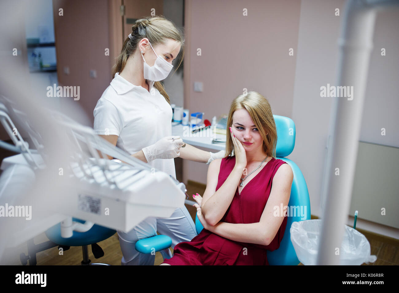 Sad patient with toothache sitting in a dental chair waiting for female ...