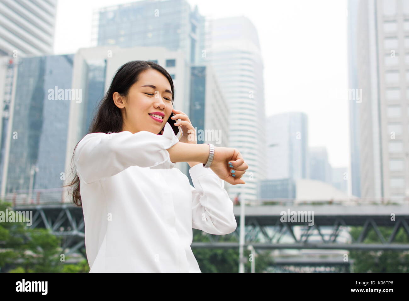 Business woman checking time while having phone call Stock Photo - Alamy