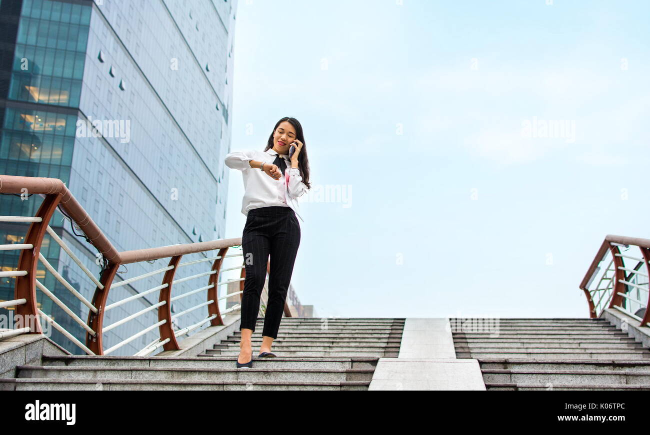 Business woman checking time while having phone call Stock Photo - Alamy
