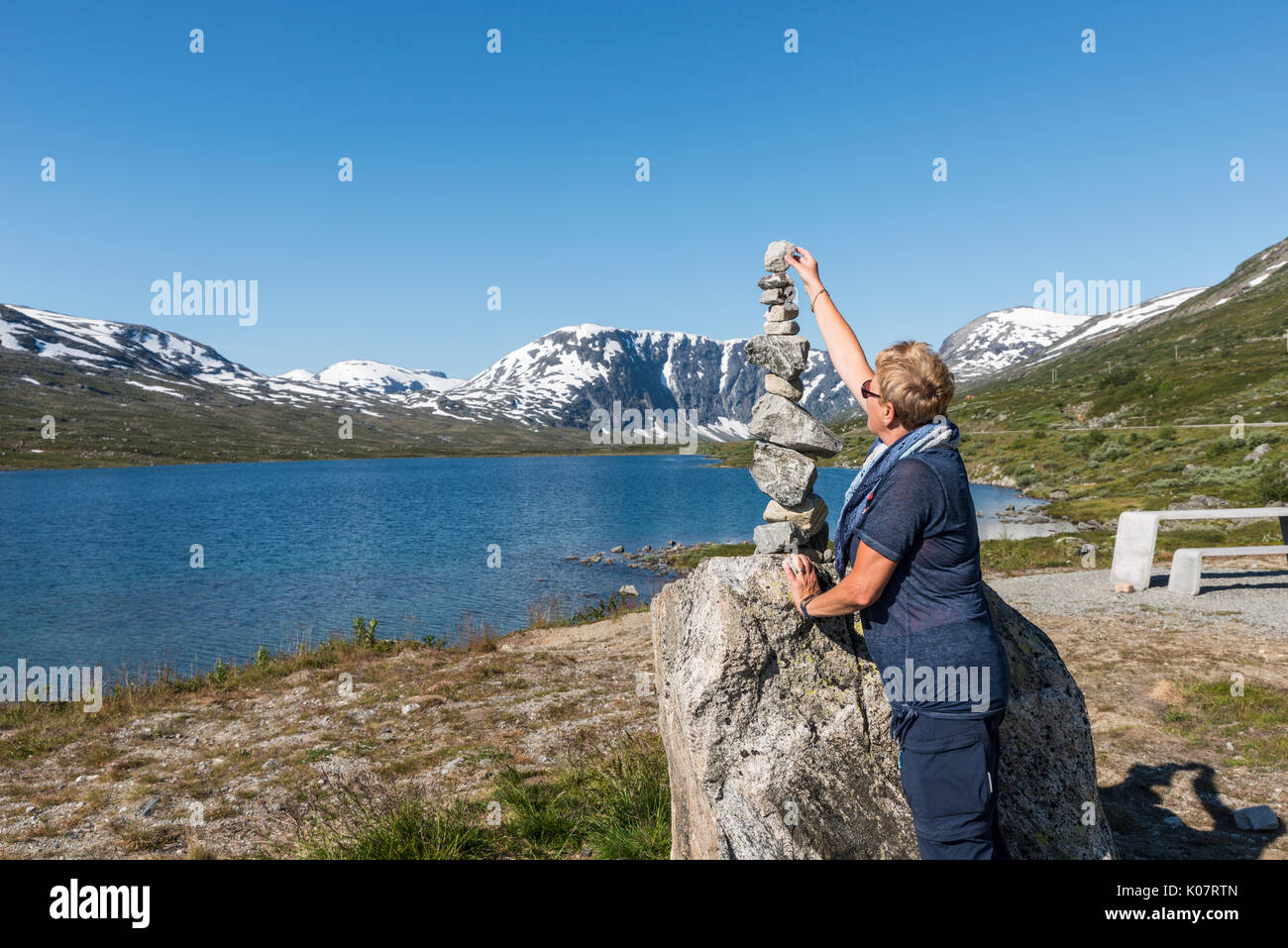 woman making stone man from stacked stones at the famous road in Norway ...