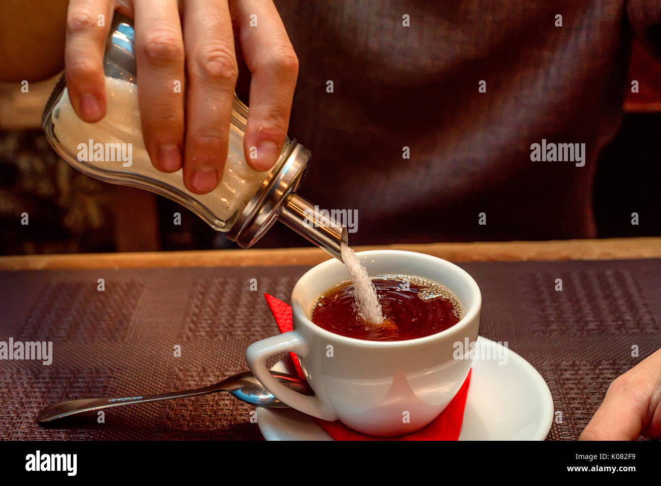 Sugar consumption concept hand adding white sugar to tea in cup Stock ...