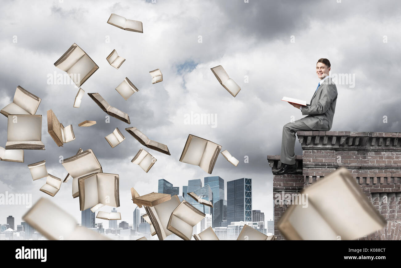 Man on roof reading book and many of them flying in air Stock Photo - Alamy