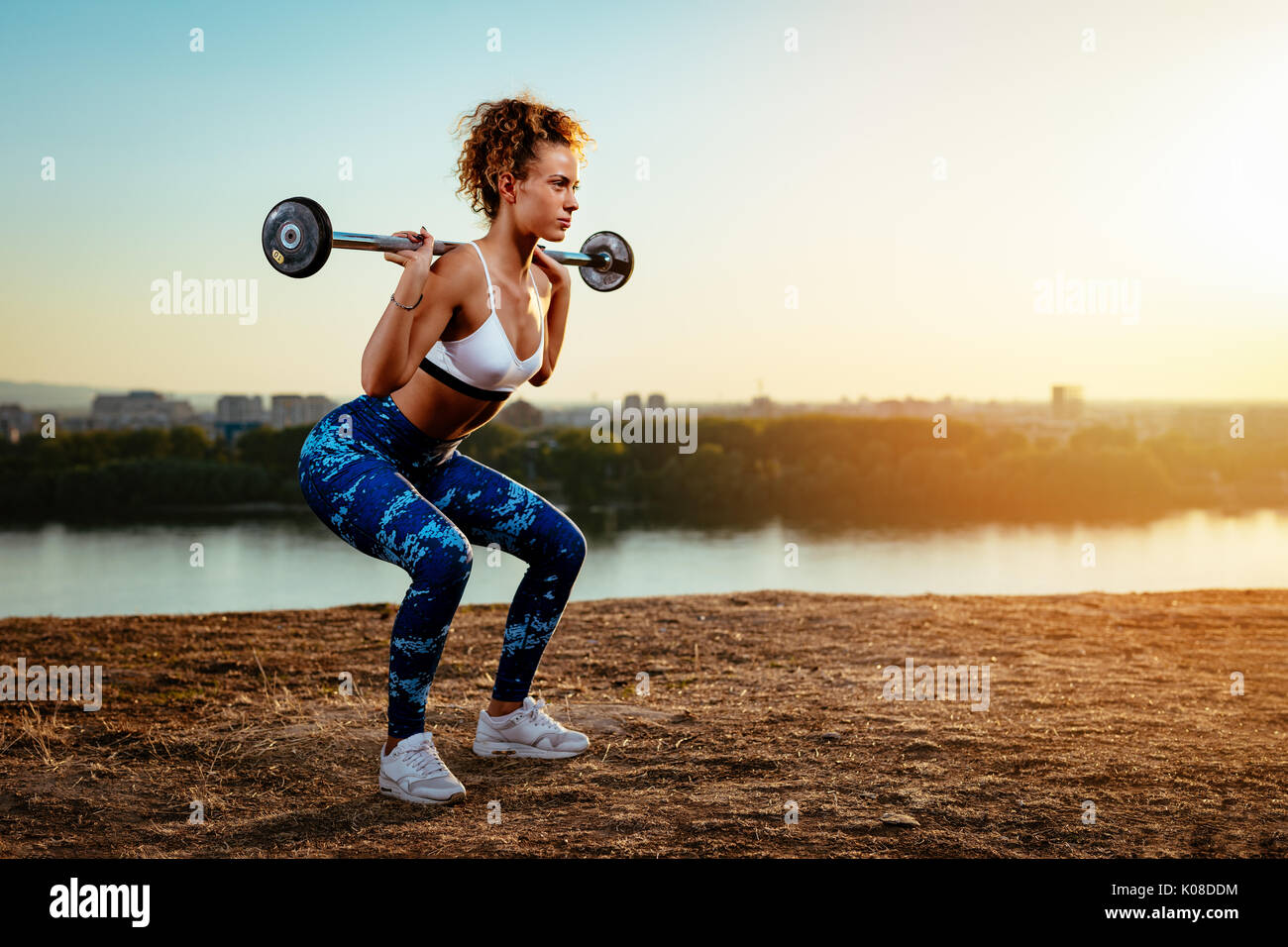 Young fitness woman doing workout with dumbbell by river on the city ...
