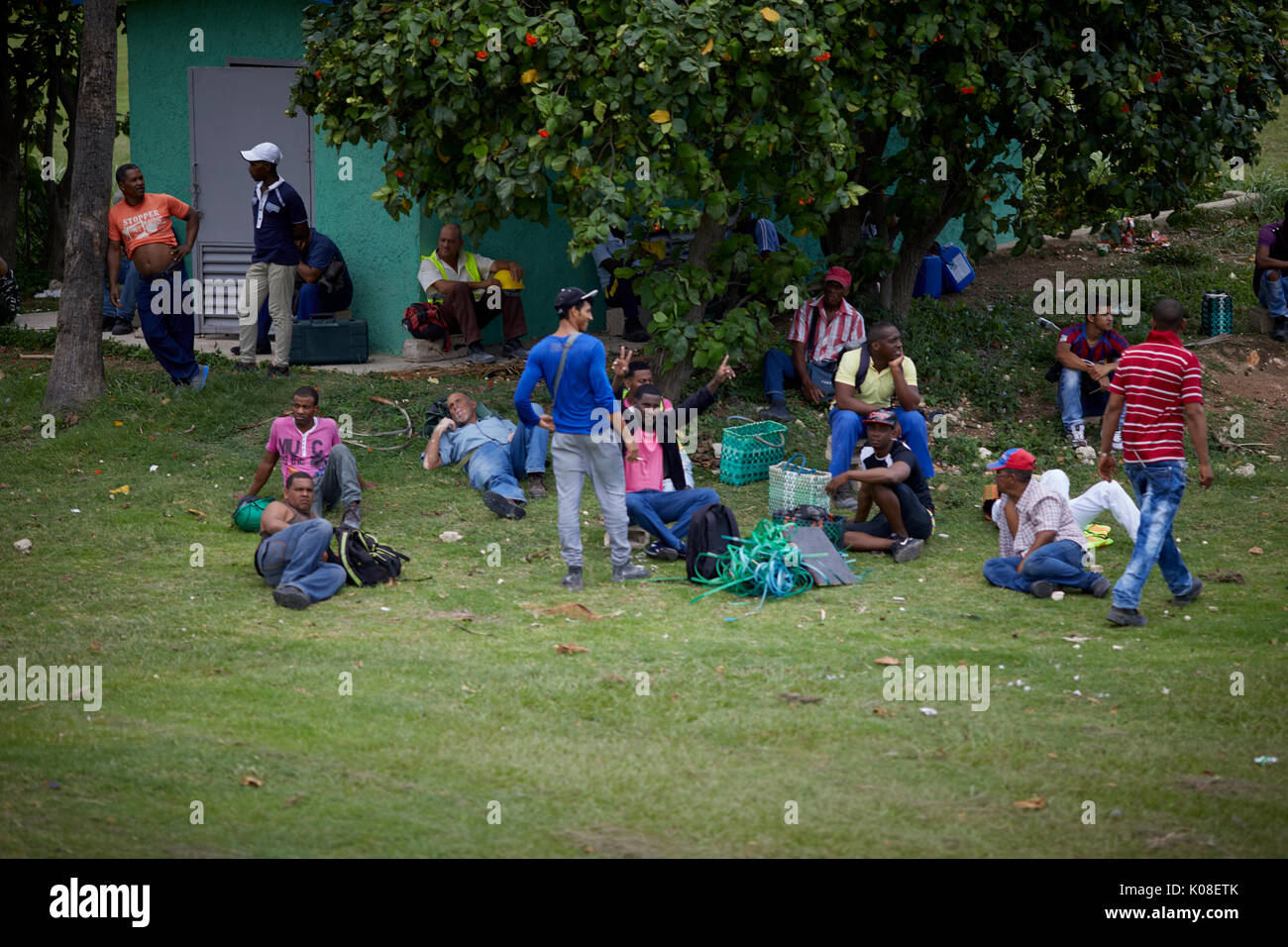 Cuban local workers shade from he sun as they wait for cheap travel ...