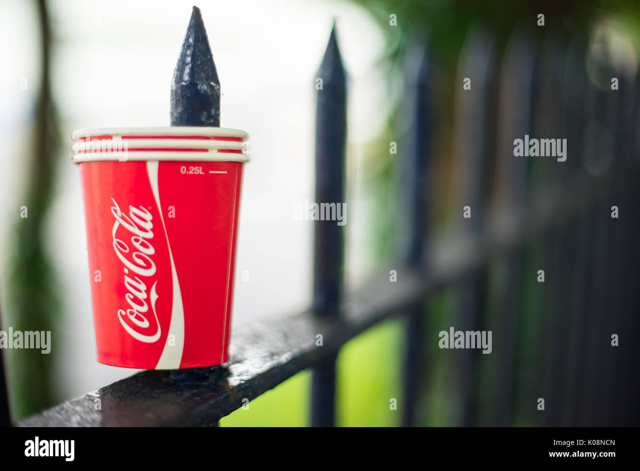Stacked red Coca Cola paper cups on a metal fence spike Stock Photo - Alamy