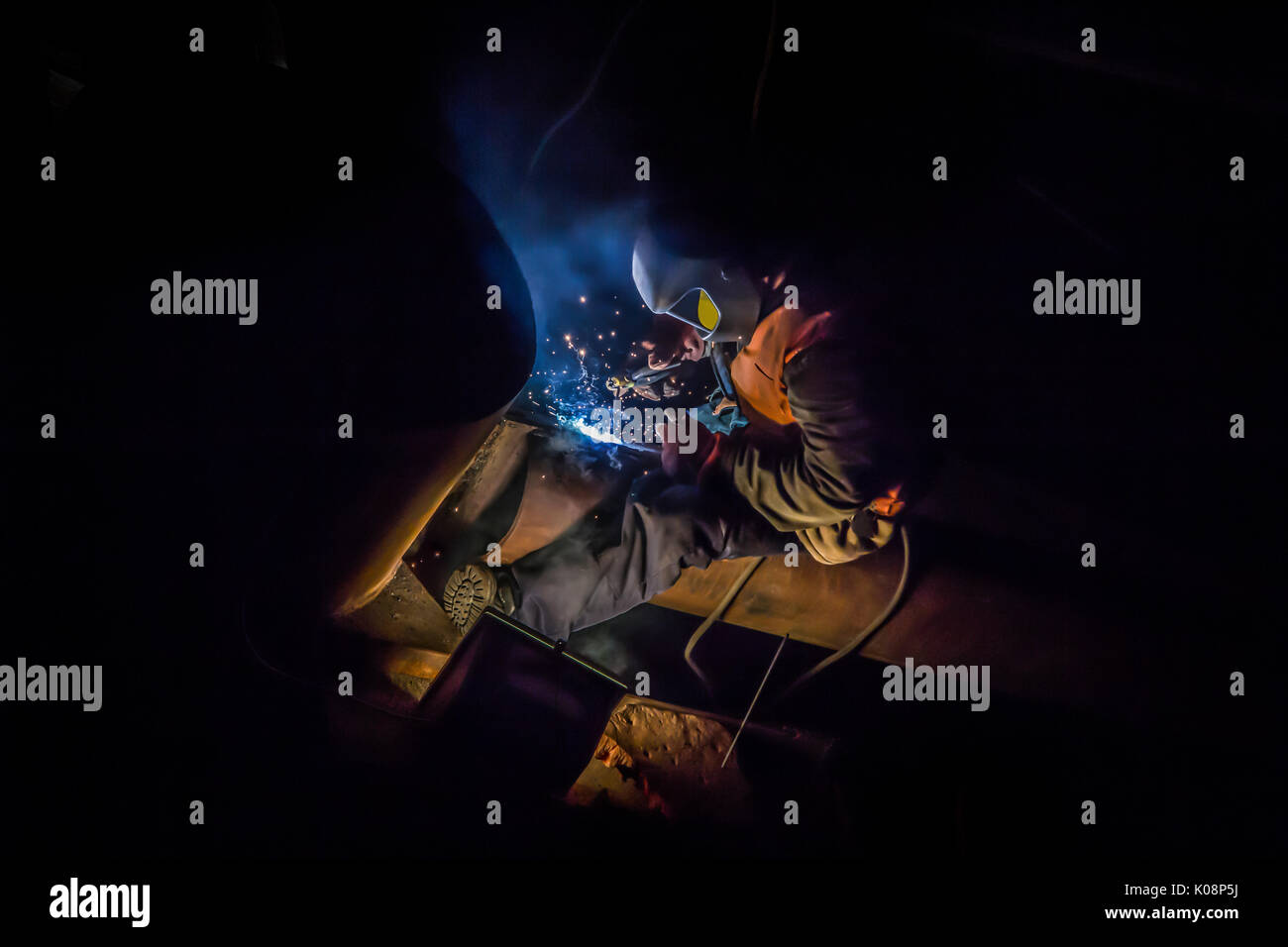 Welder worker with protective mask welding metal trunk pipeline in ...