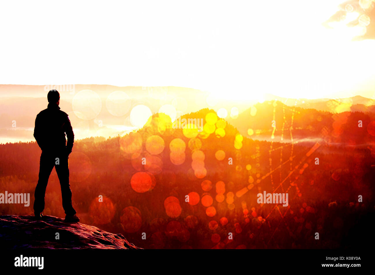 Film grain effect. Hiker stand on the sharp corner of sandstone rock in ...