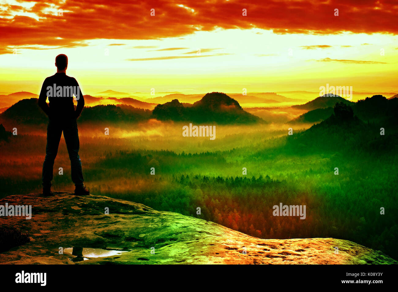 Film grain effect. Hiker is standing on the peak of sandstone rock in ...