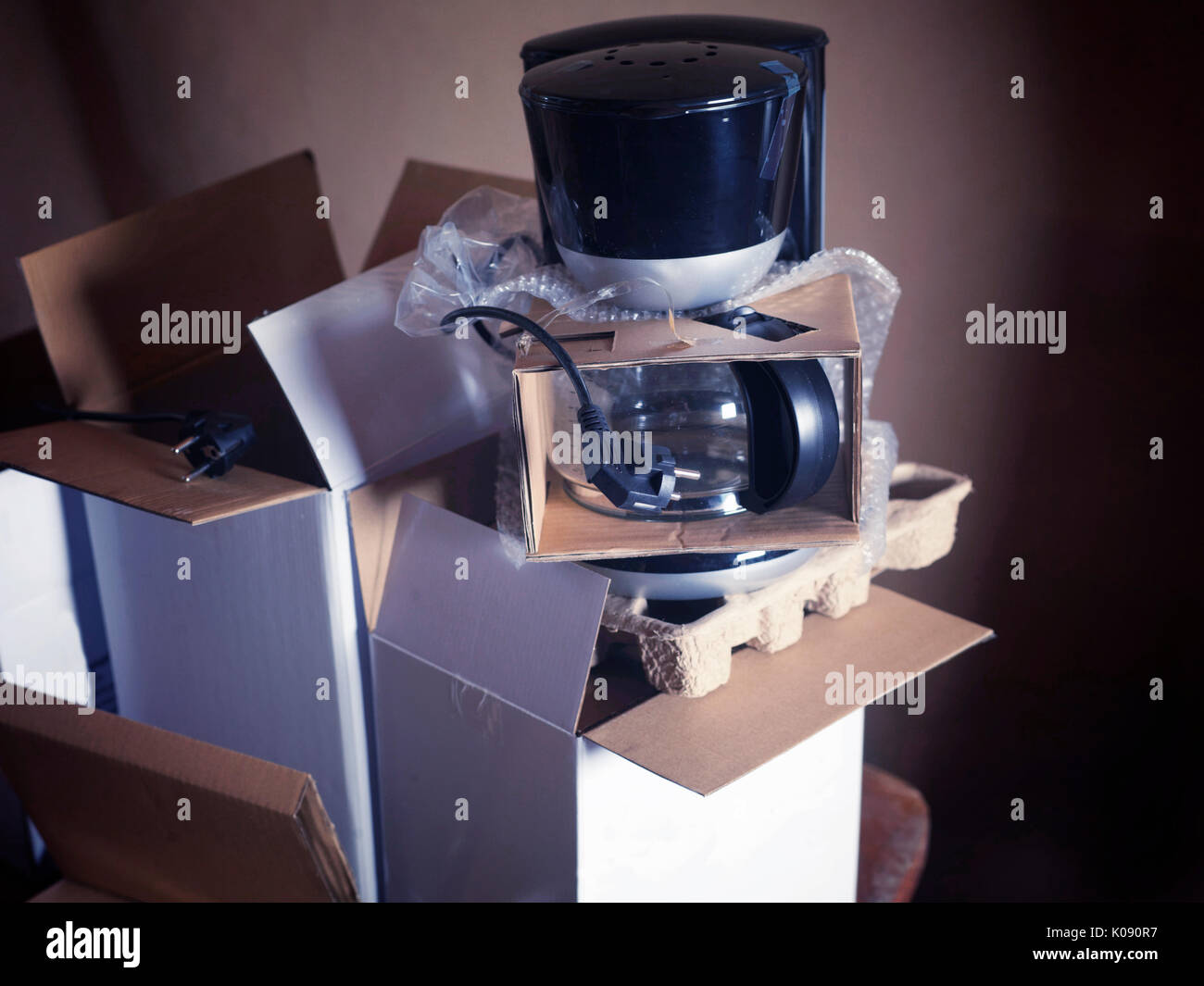 Stack opened cardboard boxes with brand new electric coffee maker on a ...