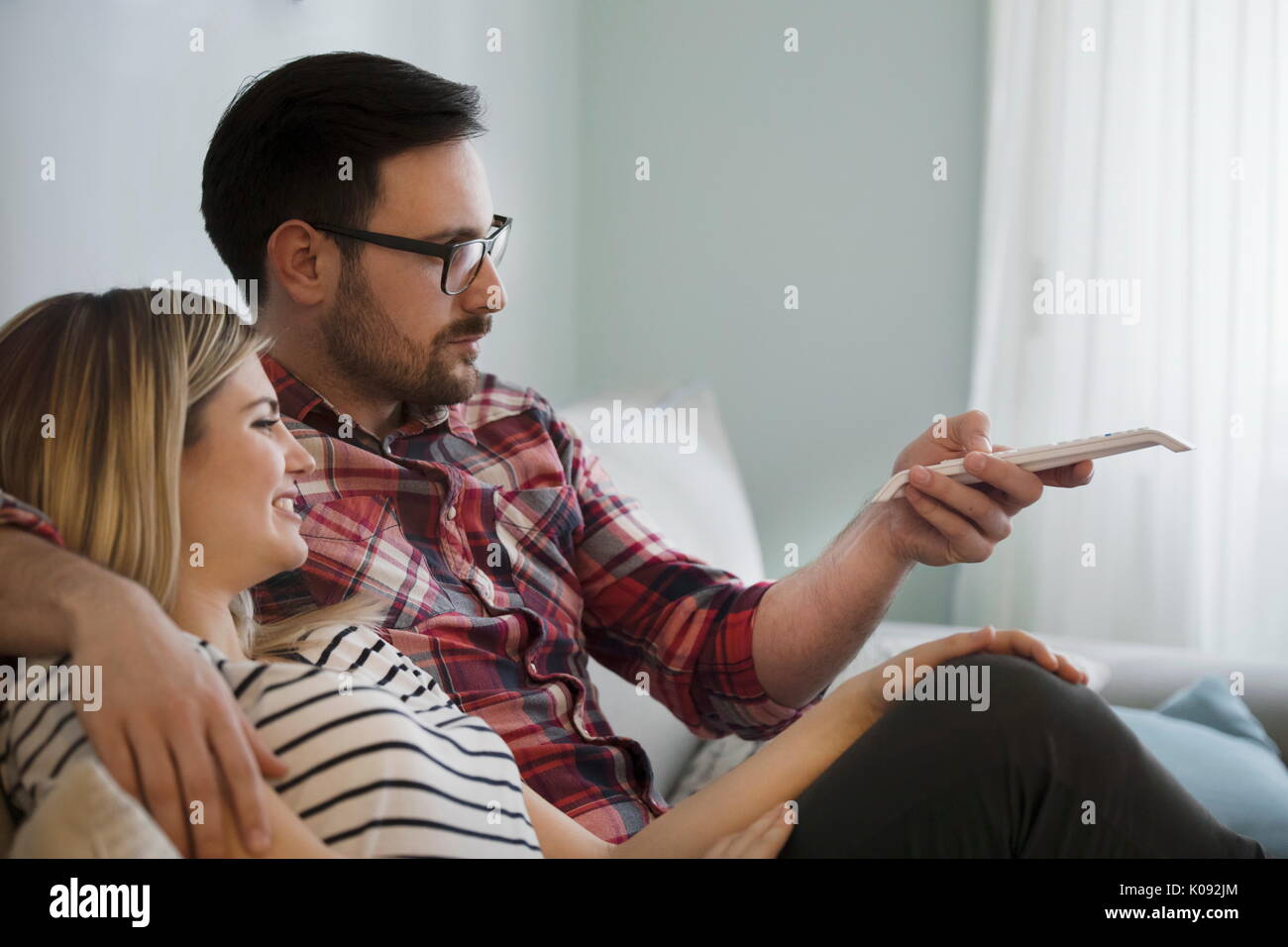 Young couple sitting on couch and watching television Stock Photo - Alamy