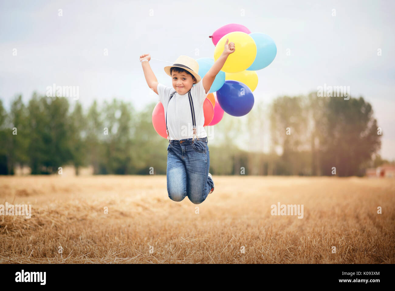 Boy jumping with balloons in the field Stock Photo - Alamy