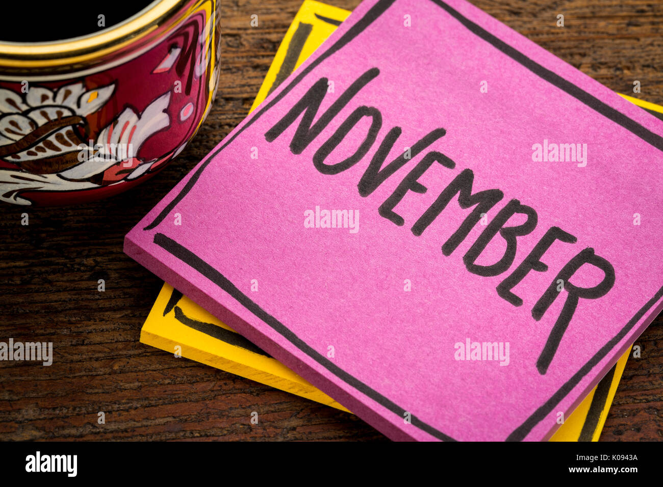 November - handwriting in black ink on a sticky note with a cup of ...