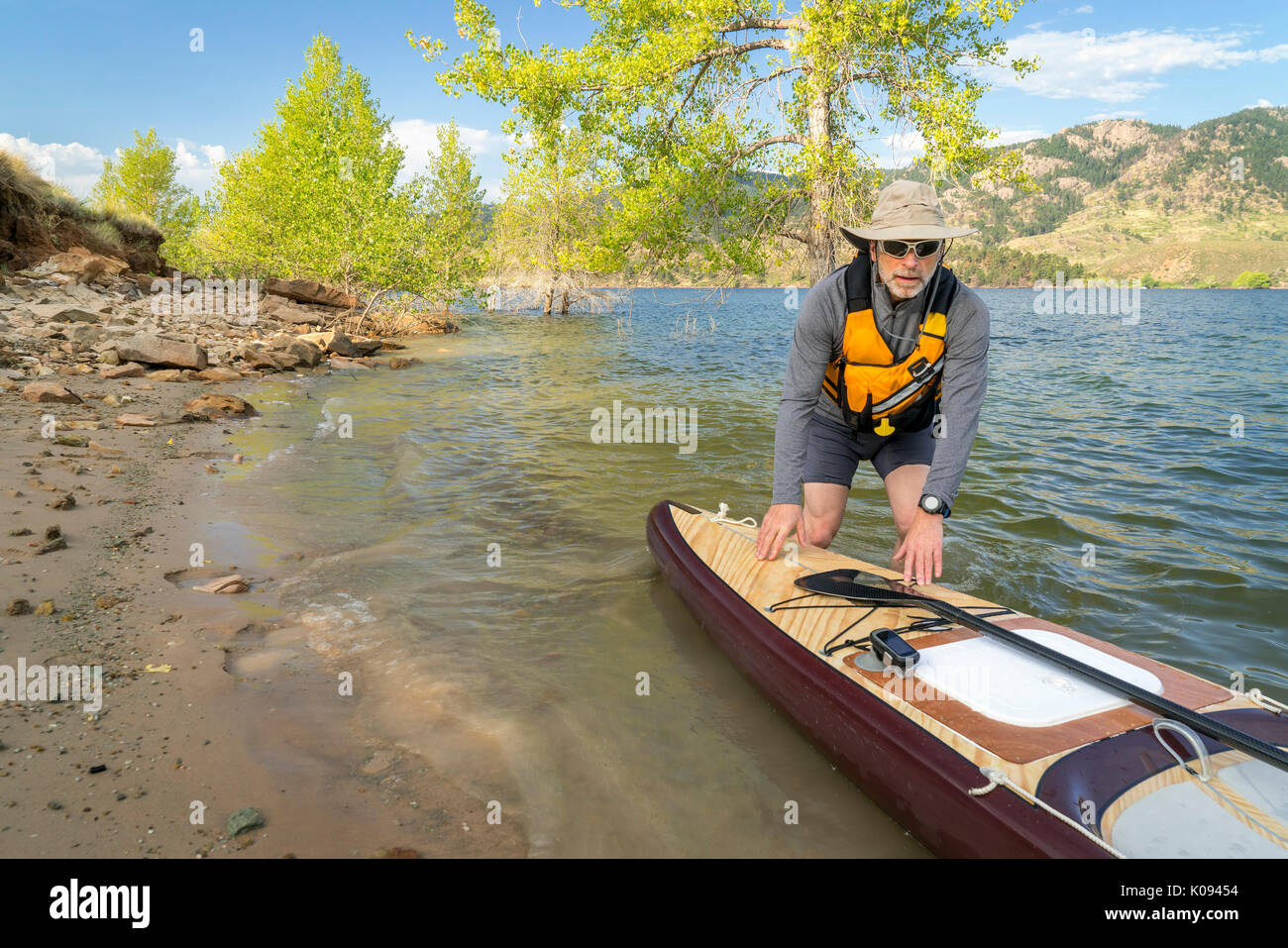 Senior paddler with a large volume expedition stand up paddleboard on a ...