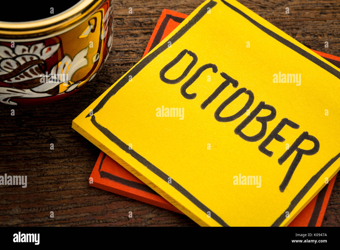 October - handwriting in black ink on a sticky note with a cup of ...