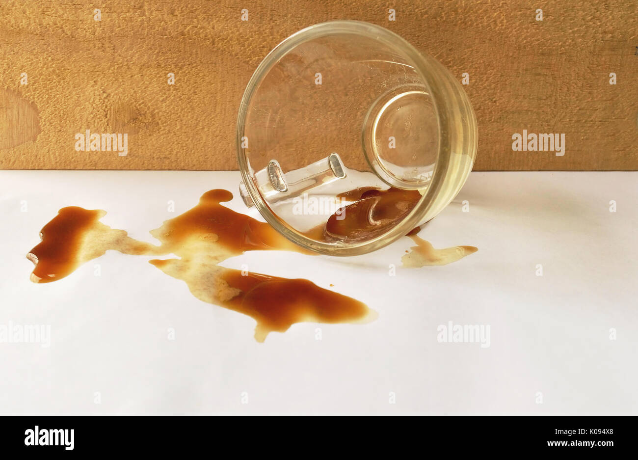 Turned coffee cup over a white surface with spilled coffee around Stock ...