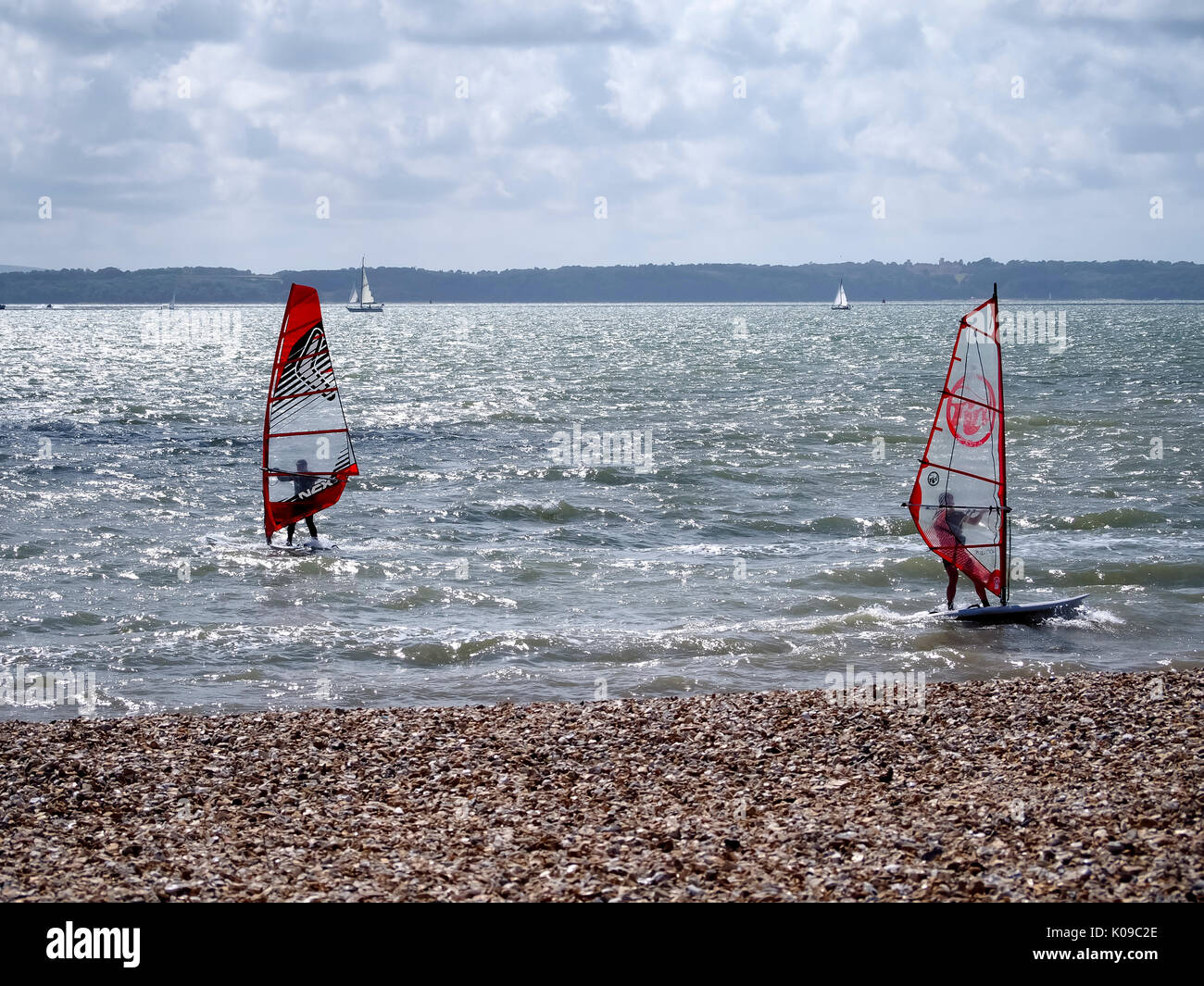 two wind surfers sails on the solent with the Isle of Wight in the ...