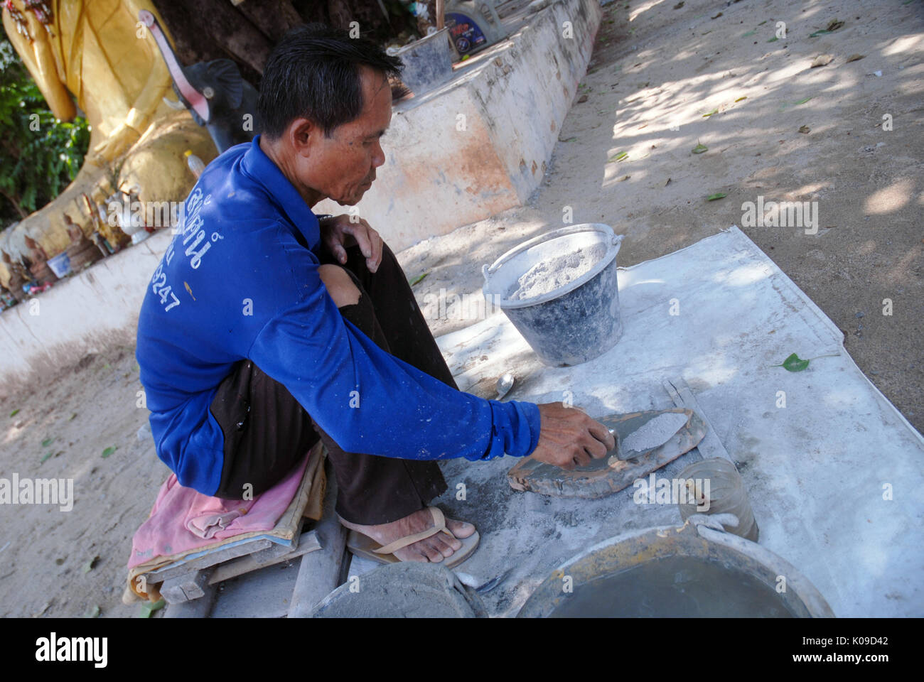 Man making concrete decorations as part of repair works to the temple ...