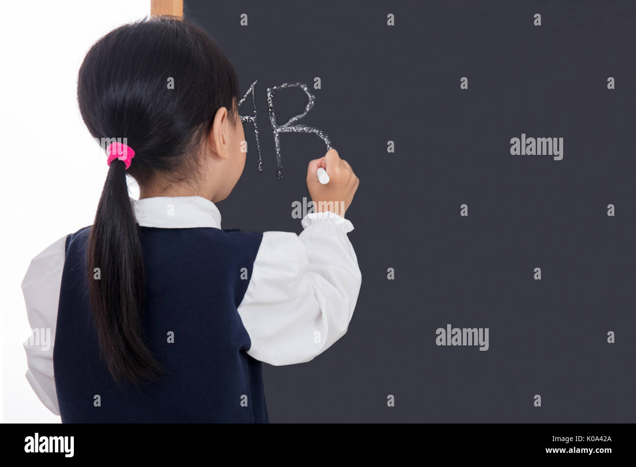 Asian Chinese little girl writing on blackboard in isolated white ...