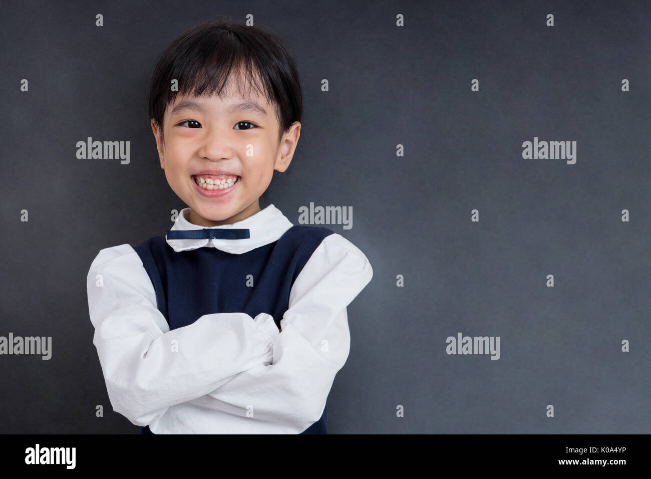 Asian Chinese little girl standing in front of blackboard in isolated ...