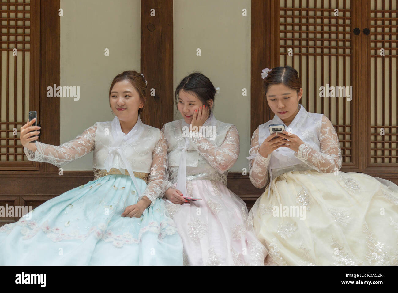 Three young women in traditional Korean outfit pose for a selfie in ...
