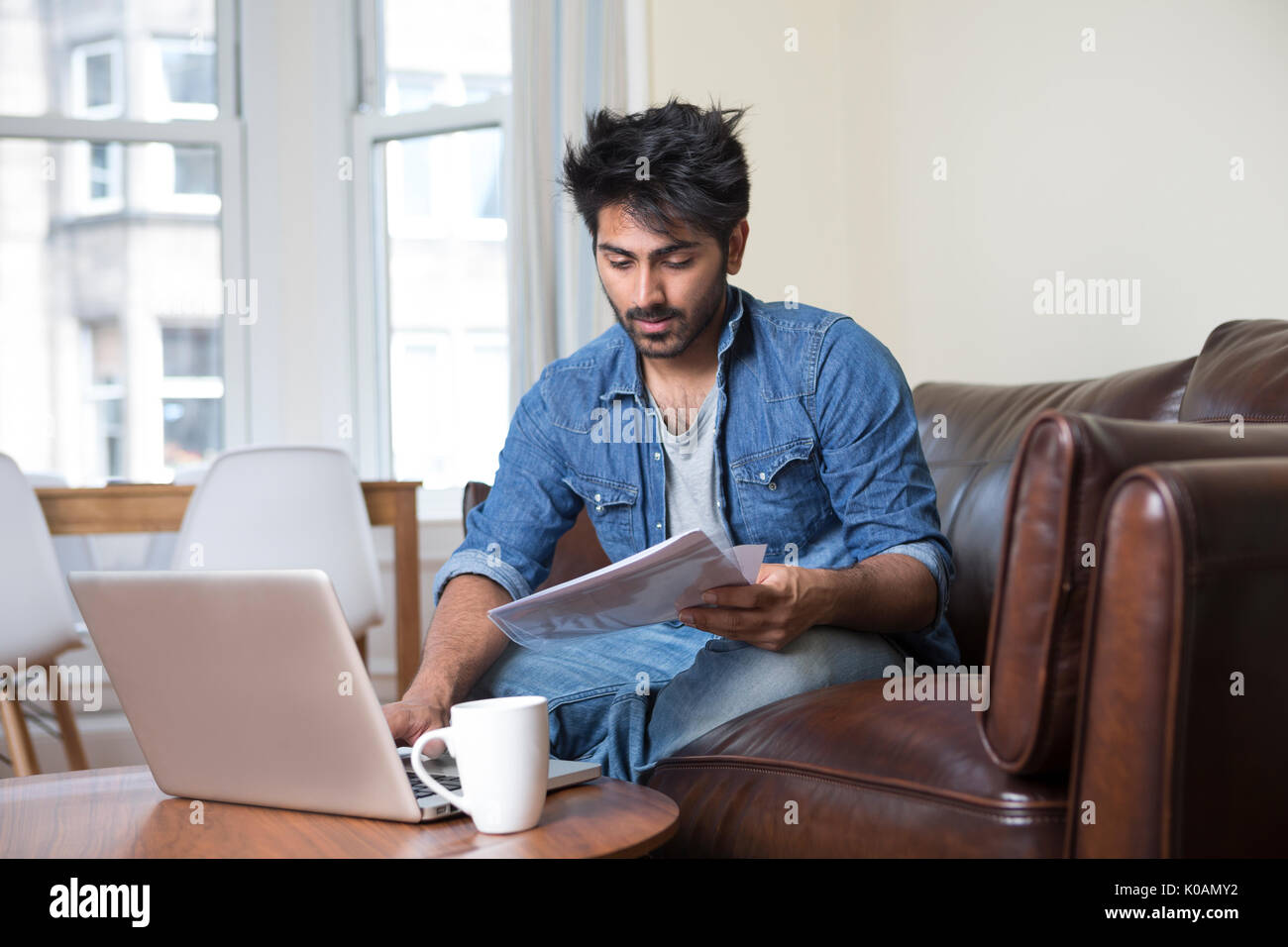 Indian man at home on sofa using a laptop Stock Photo - Alamy