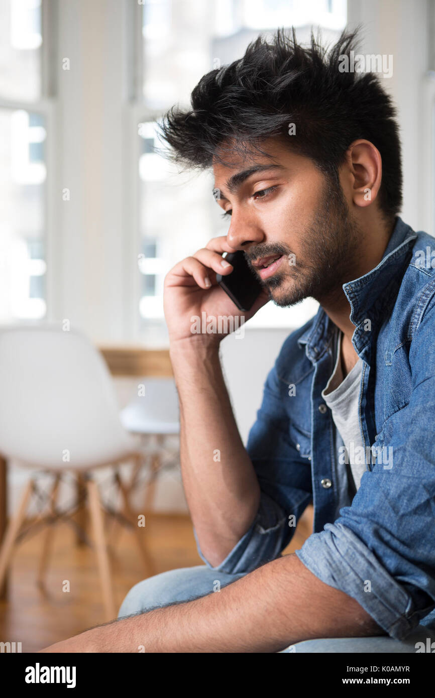 Asian Man using his phone at home in the lounge Stock Photo - Alamy