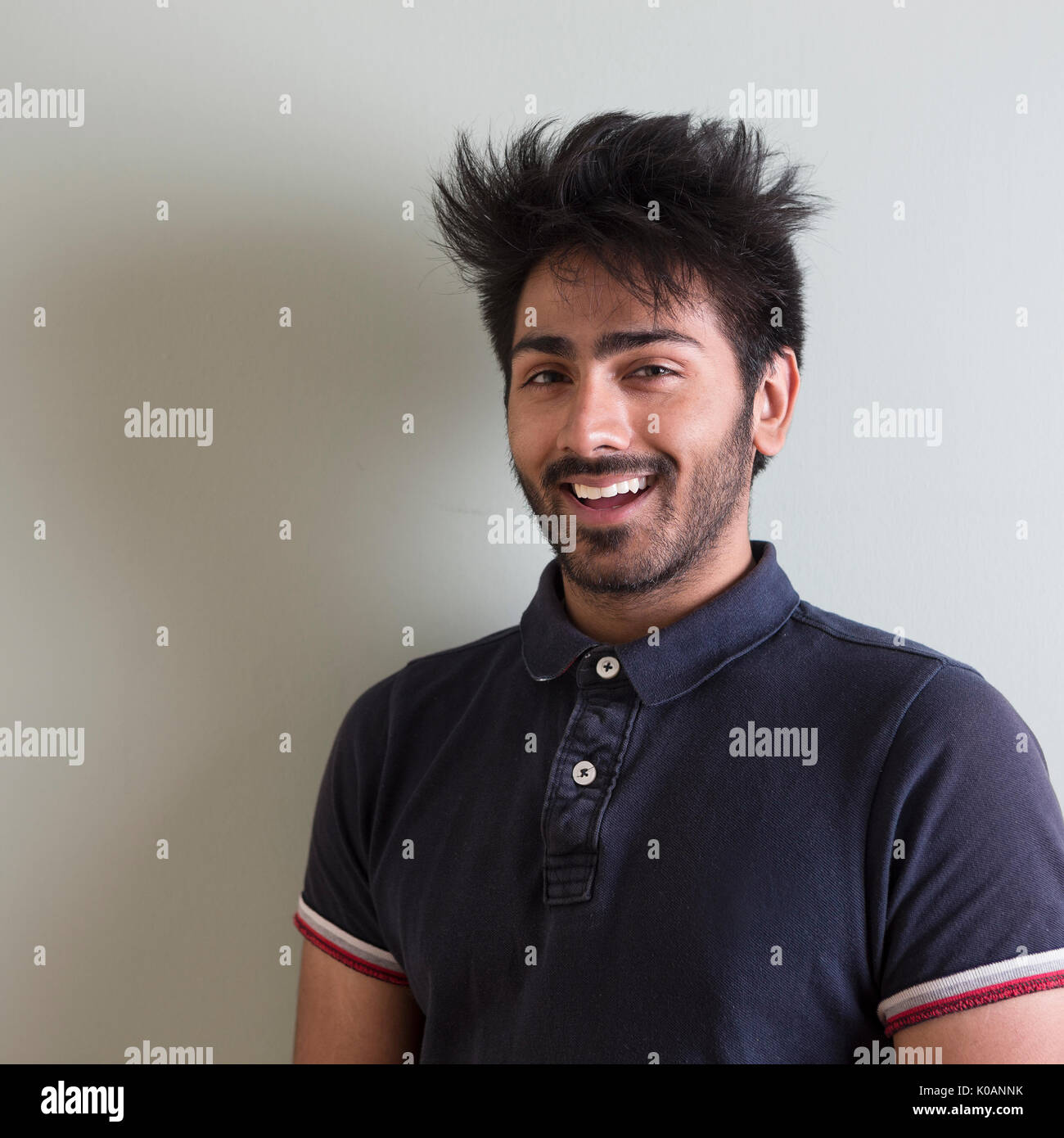 Portrait of a happy Indian man standing against green wall Stock Photo ...