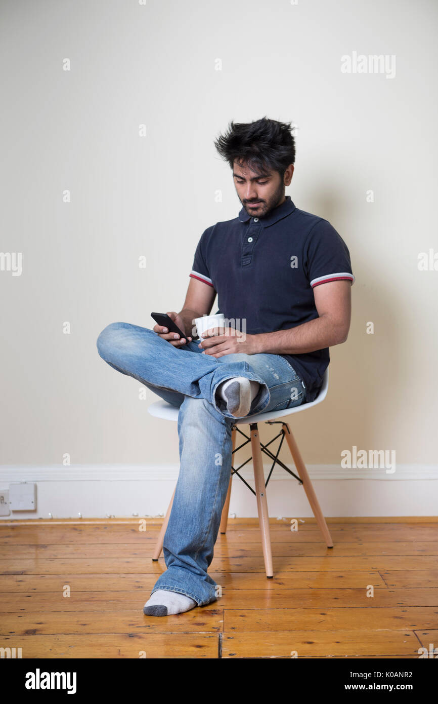 Portrait of a trendy Asian Man sitting using his phone Stock Photo - Alamy