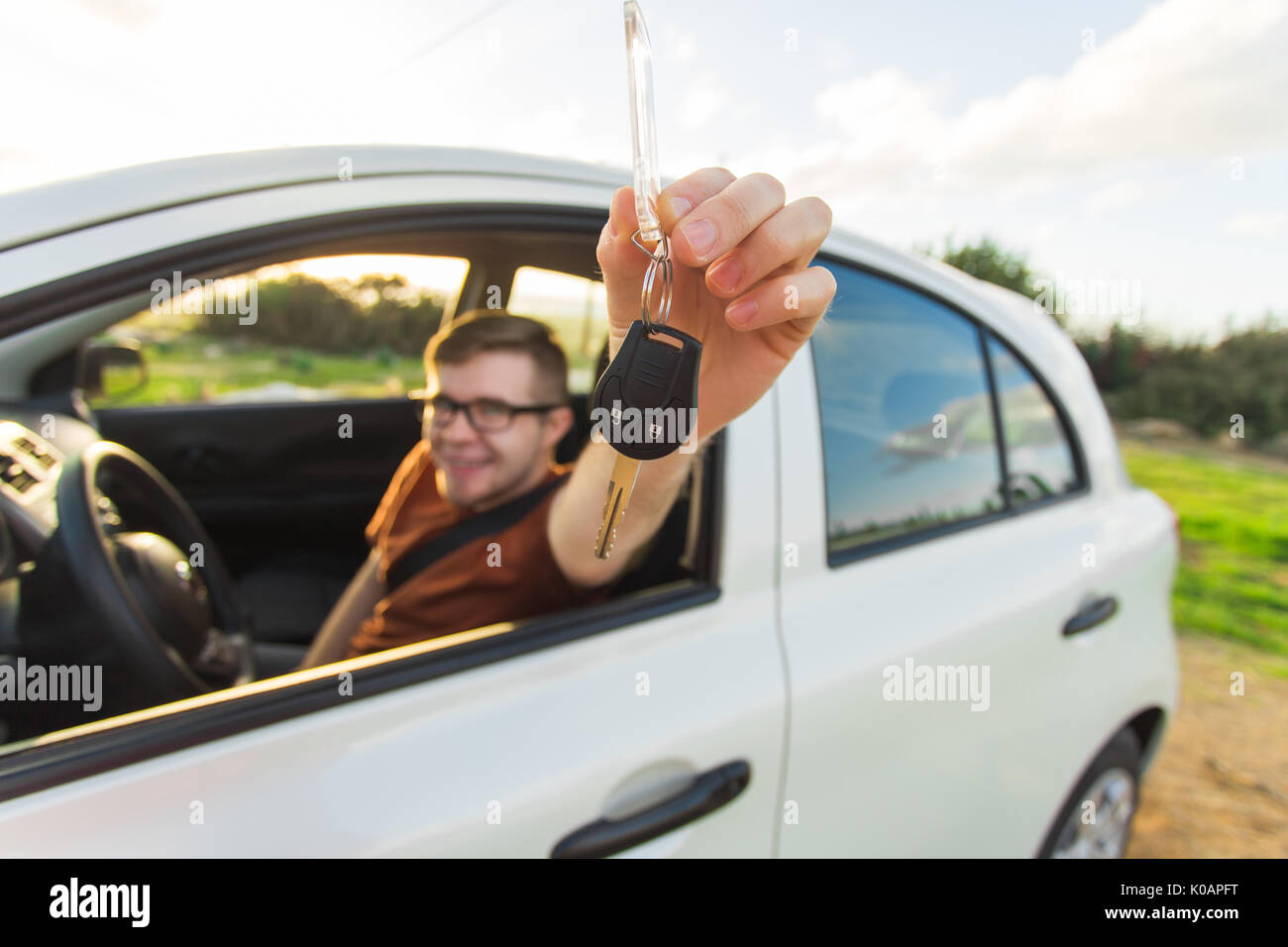 Young man smiling and holding key in his car. Auto purchase and people ...