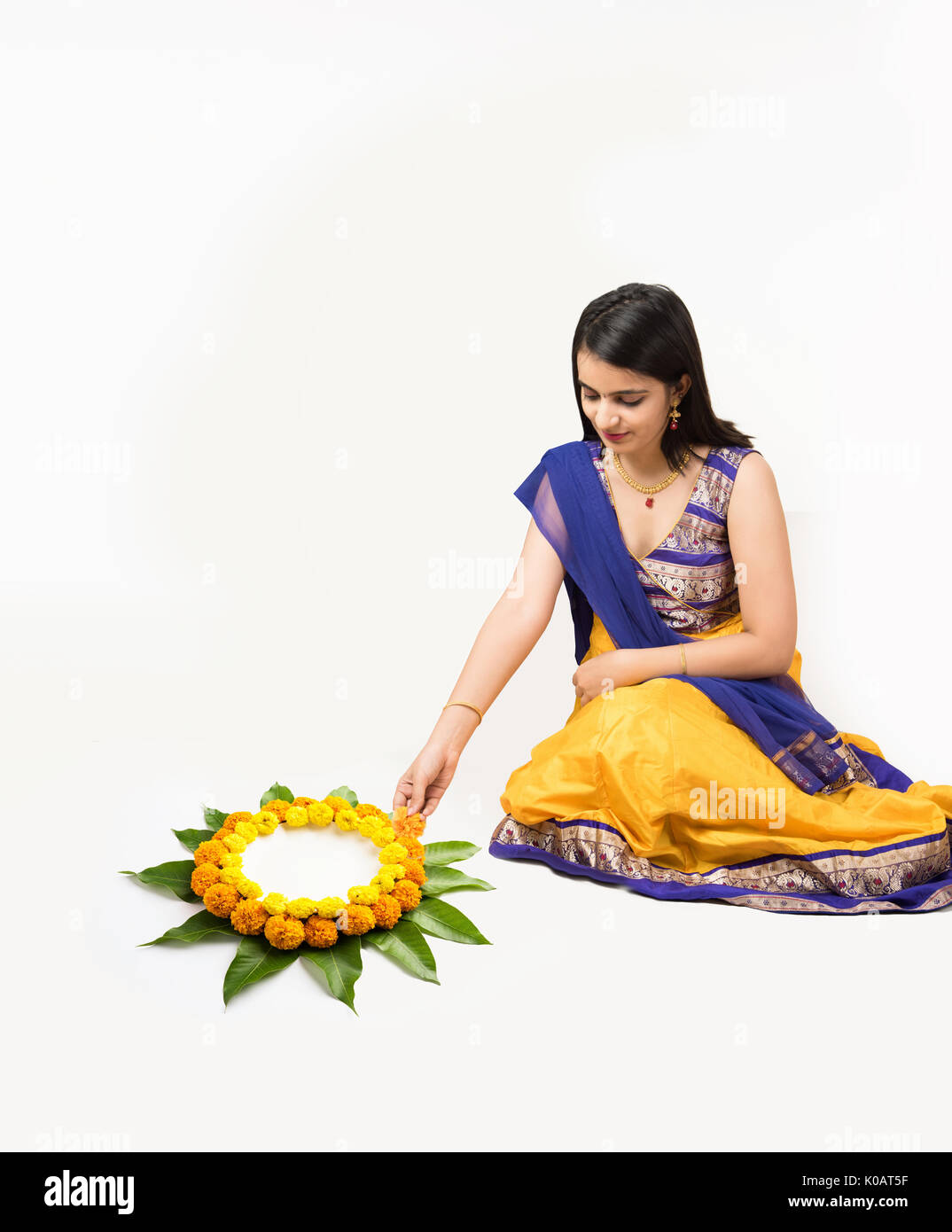 Indian woman or young girl making floral or flower rangoli for diwali ...