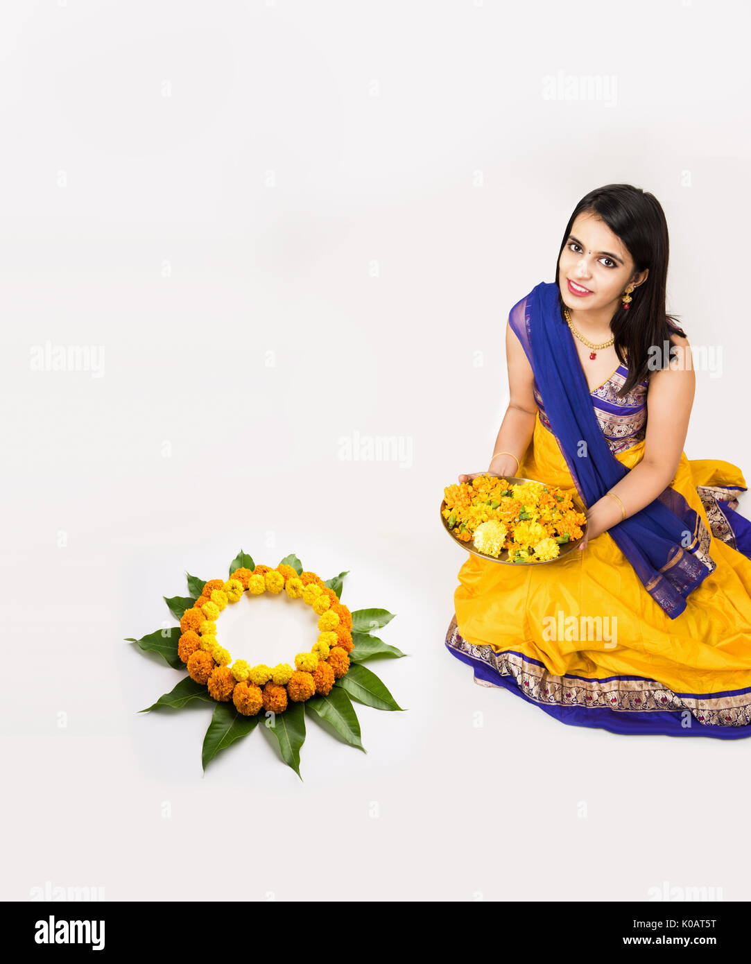 Indian woman or young girl making floral or flower rangoli for diwali ...