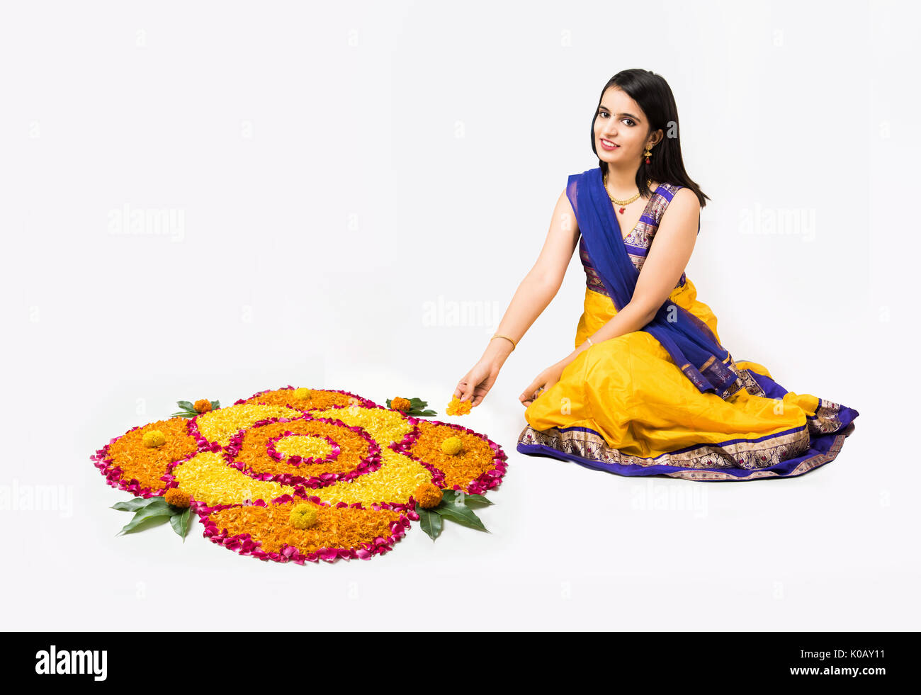 Indian woman or young girl making floral or flower rangoli for diwali ...