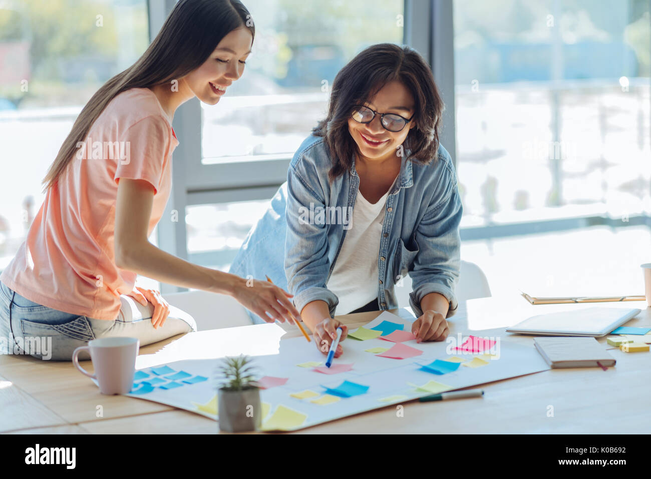 Pleasant smart friends doing a project Stock Photo - Alamy