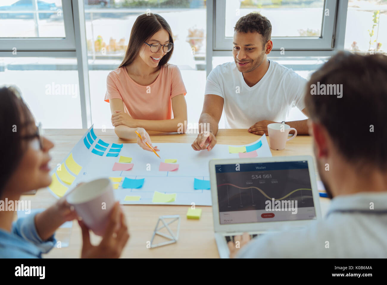 Nice young people sitting around the table Stock Photo - Alamy