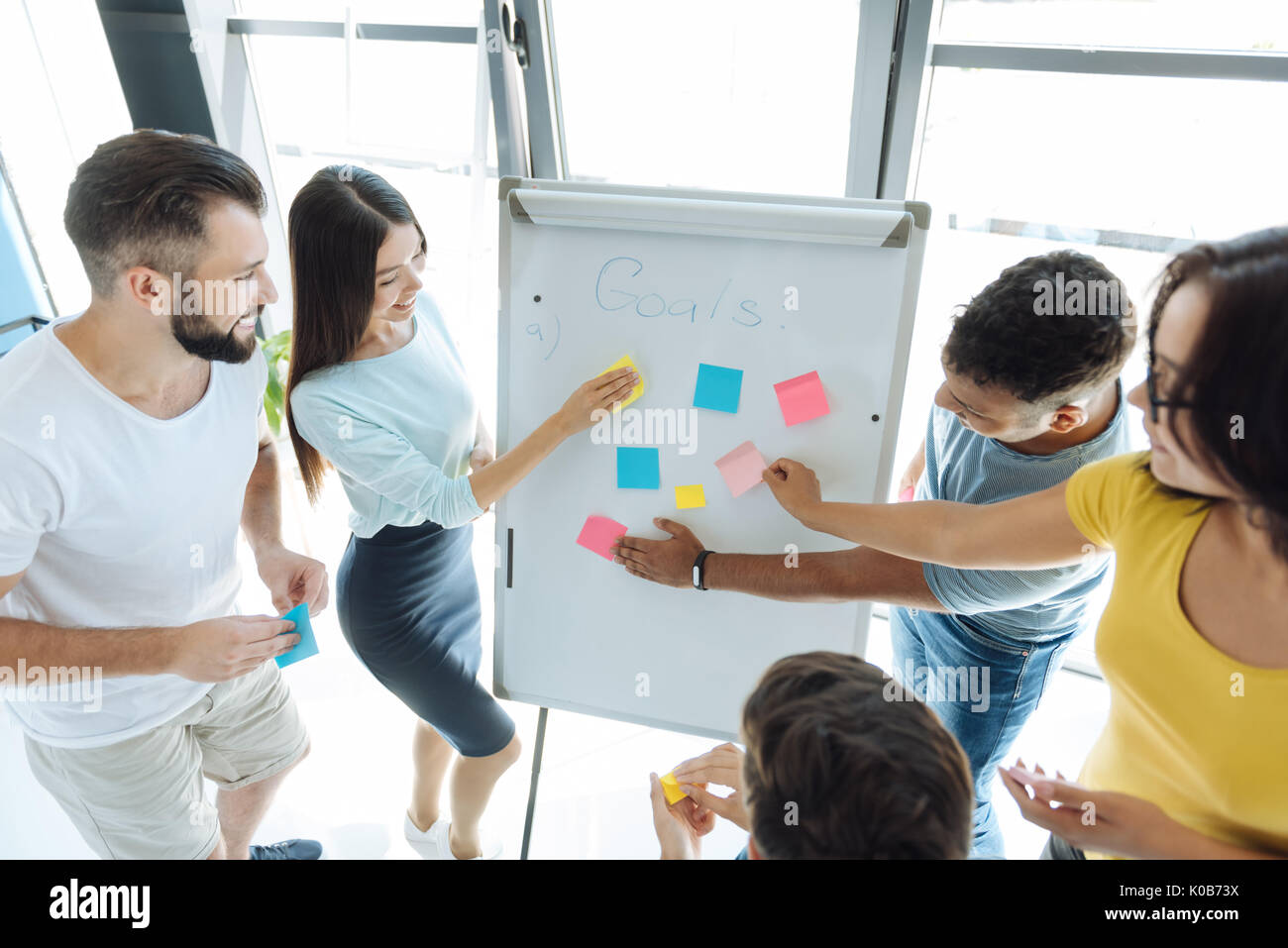 Delighted positive people putting sticky notes to the whiteboard Stock ...