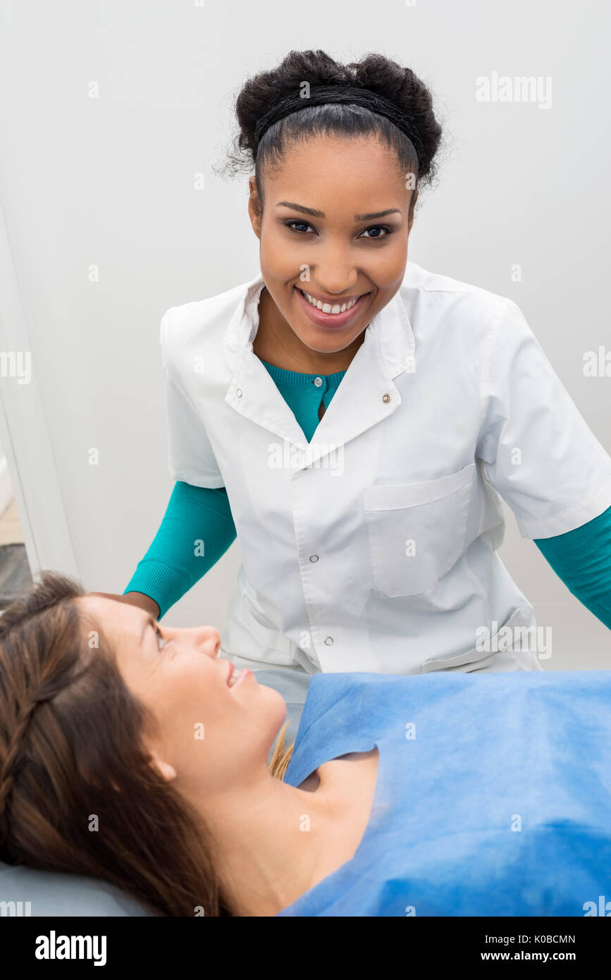 Smiling Doctor Standing By Female Patient Undergoing X-ray Scan Stock ...
