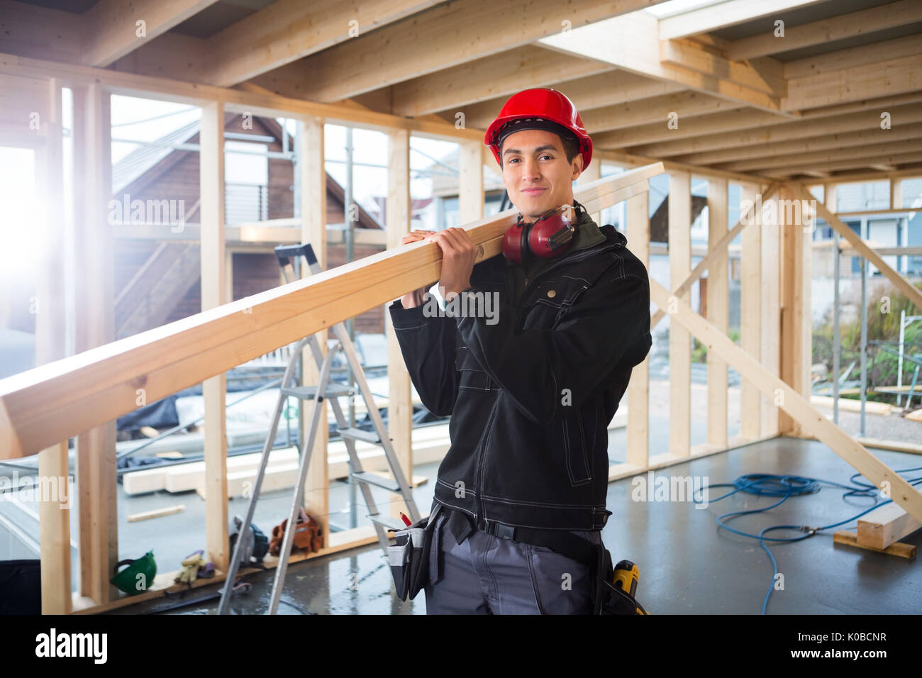 Young Carpenter Carrying Wood On Shoulder At Construction Site Stock ...