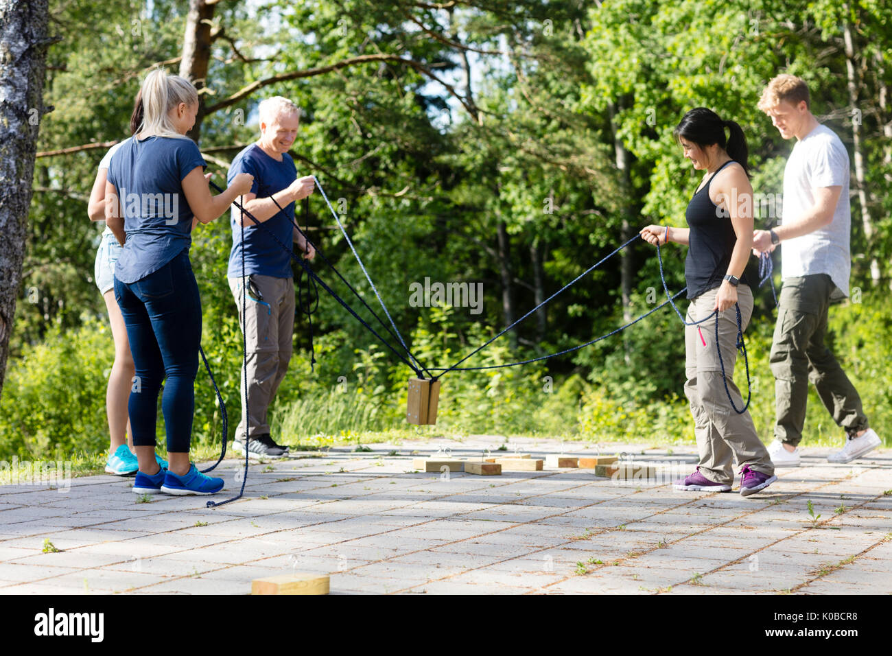 Full Length Of Friends Picking Wooden Blocks With Ropes Stock Photo - Alamy