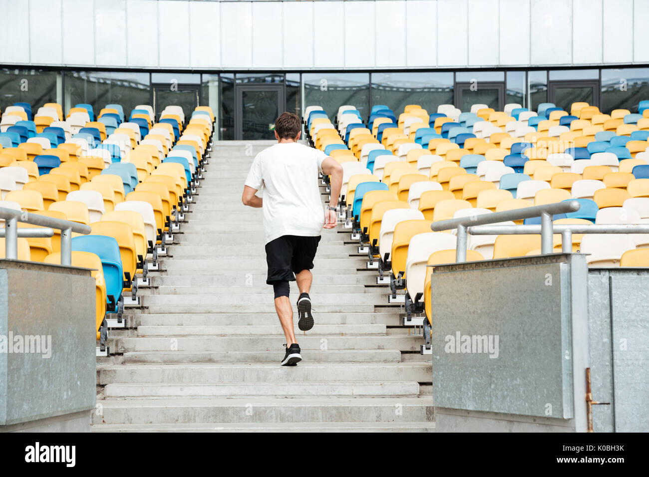 Back view of a young man running upstairs at the stadium Stock Photo ...