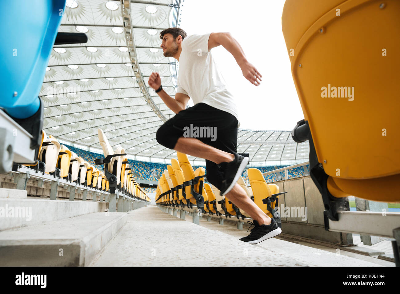Side view of a young male runner running upstairs at the stadium Stock ...