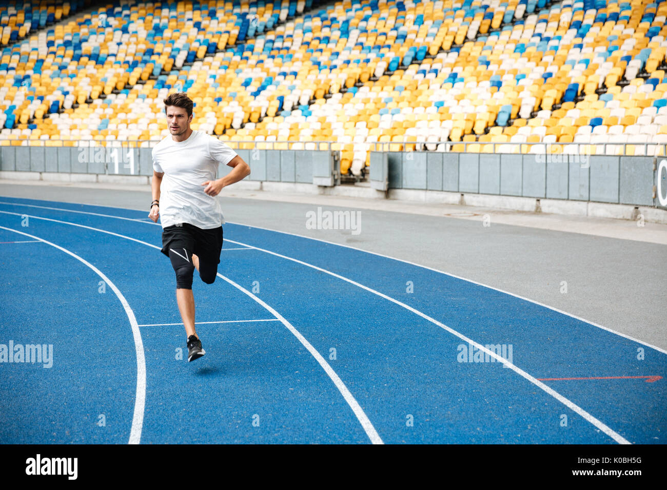 Young sprinter running on athletics track at the stadium Stock Photo ...