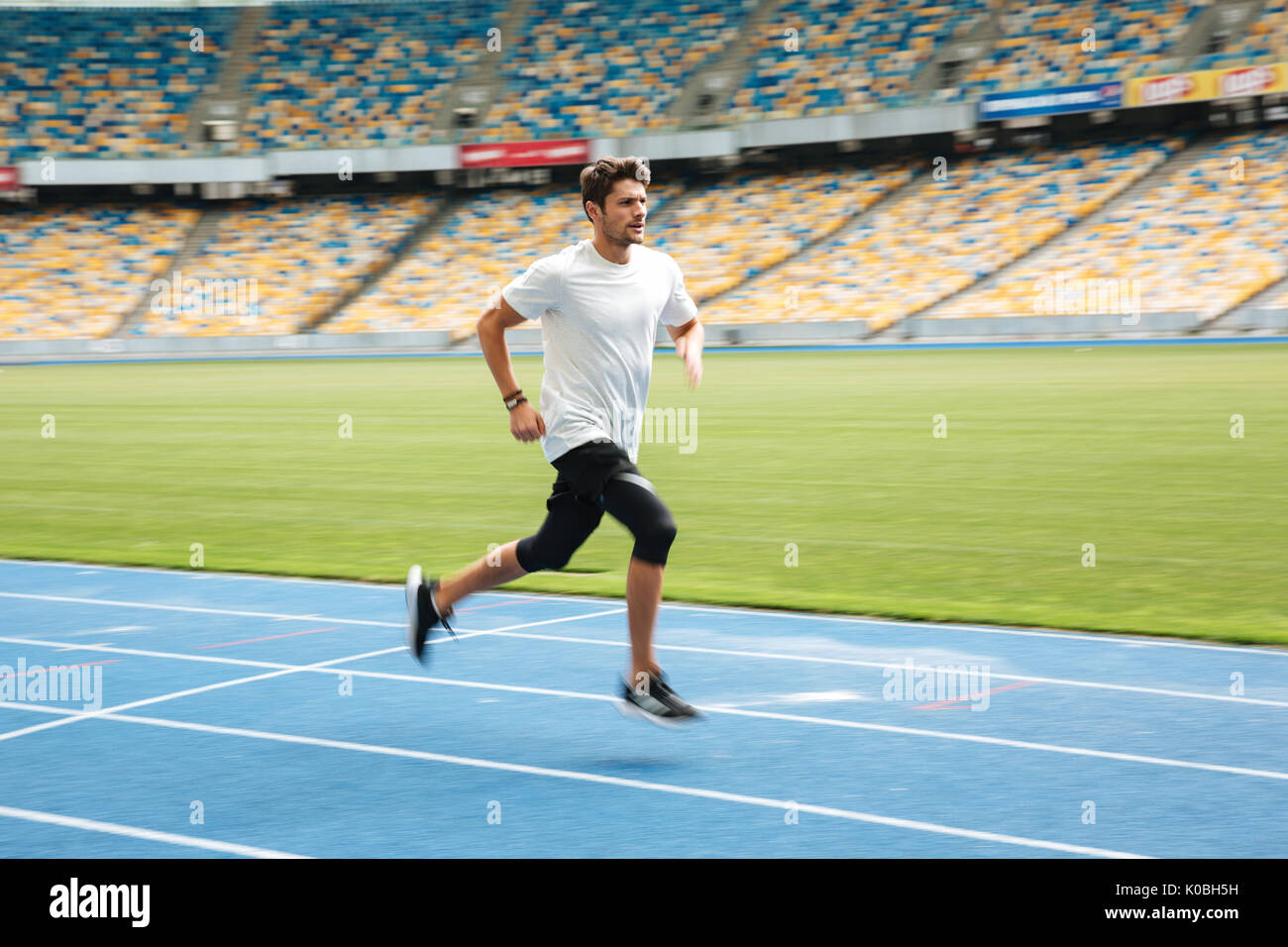 Side view of a young professional sprinter running on racetrack Stock ...