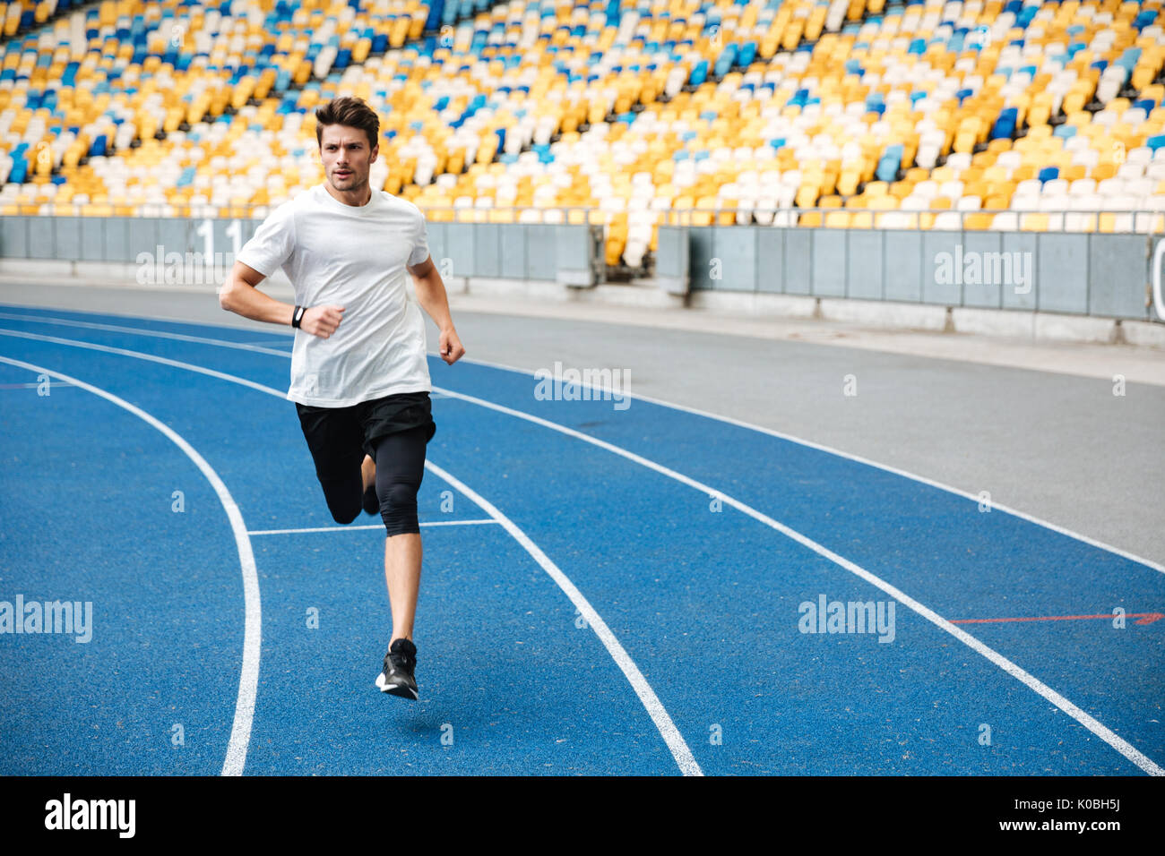 Athlete man running on a racetrack at a stadium Stock Photo - Alamy