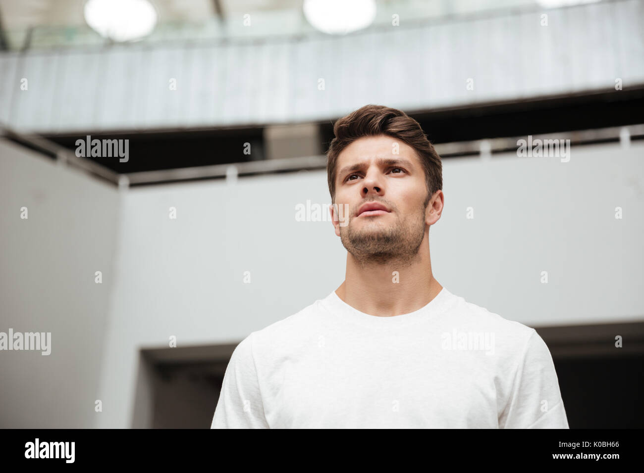 Picture of young sports man standing near grey wall outdoors and ...
